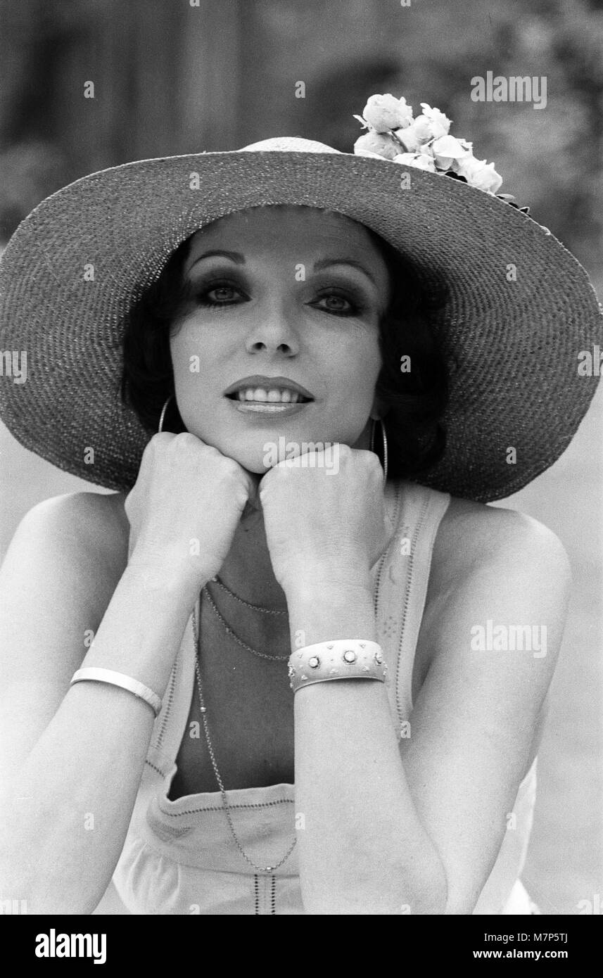 Actress Joan Collins modelling outfits that she will wear on a trip to ...