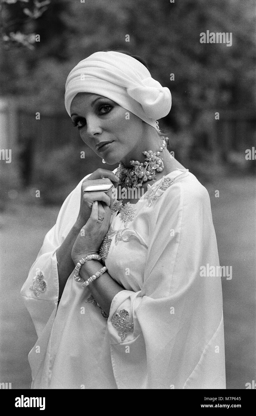 Actress Joan Collins modelling outfits that she will wear on a trip to ...