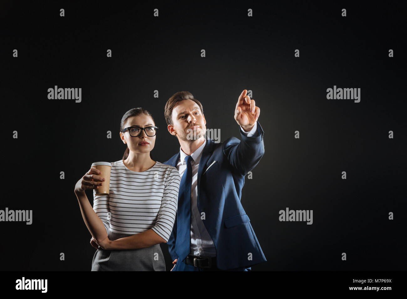 Clever curious partners standing and working with the object Stock ...