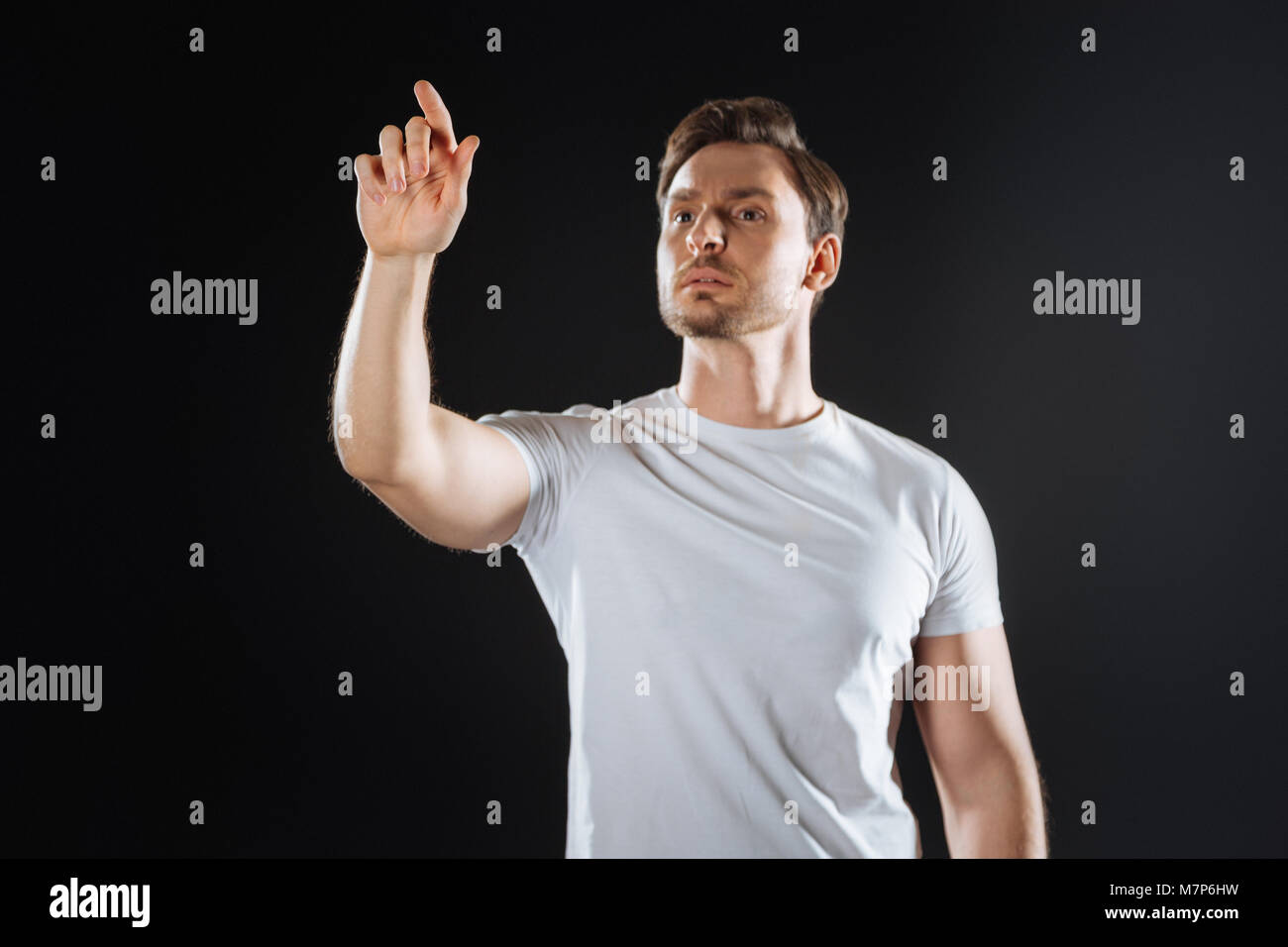 Handsome thoughtful man standing and lifting hand Stock Photo - Alamy