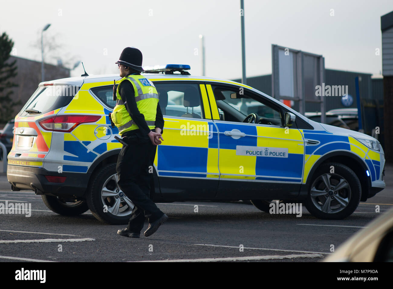 policeman with arms behind his back and hands clasped walks in front of ...