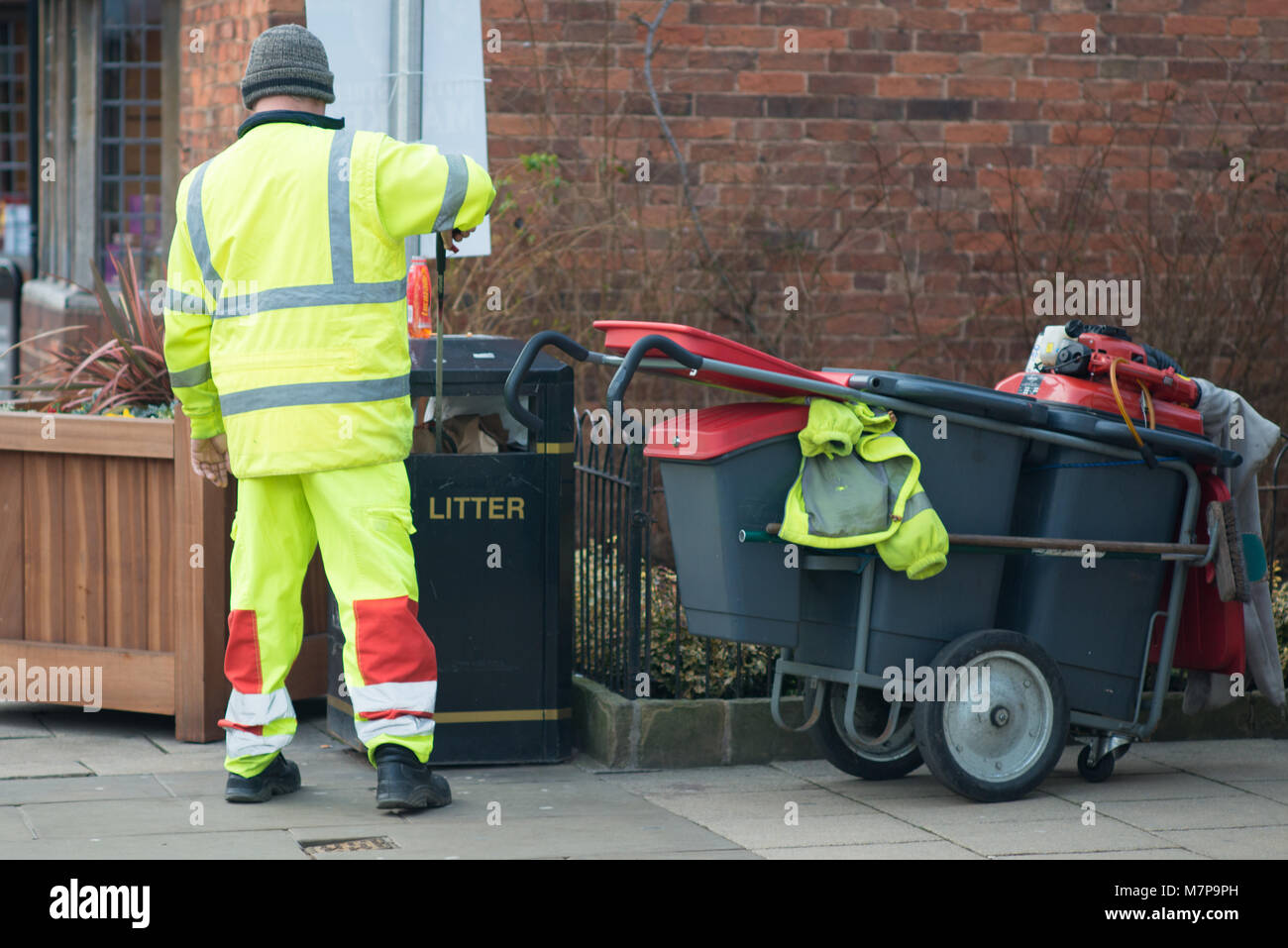 street cleaner with collecting stick grabs litter and puts it into ...