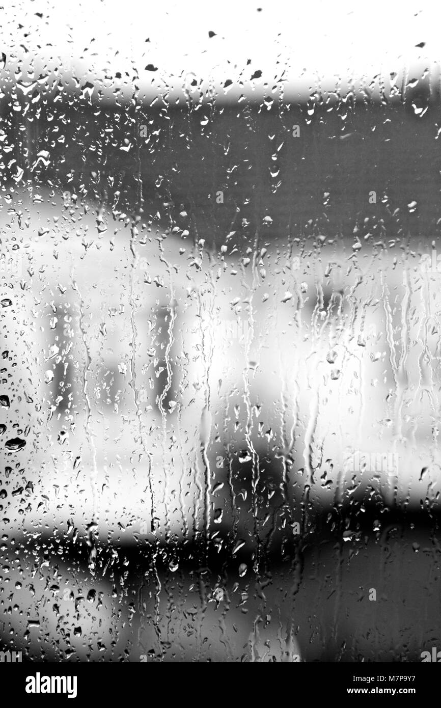 Monochrome abstract view from a rain covered window with the raindrops ...