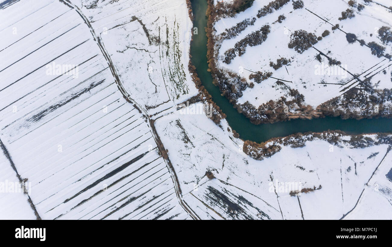 Aerial view riverbend passing snow covered fields Stock Photo - Alamy
