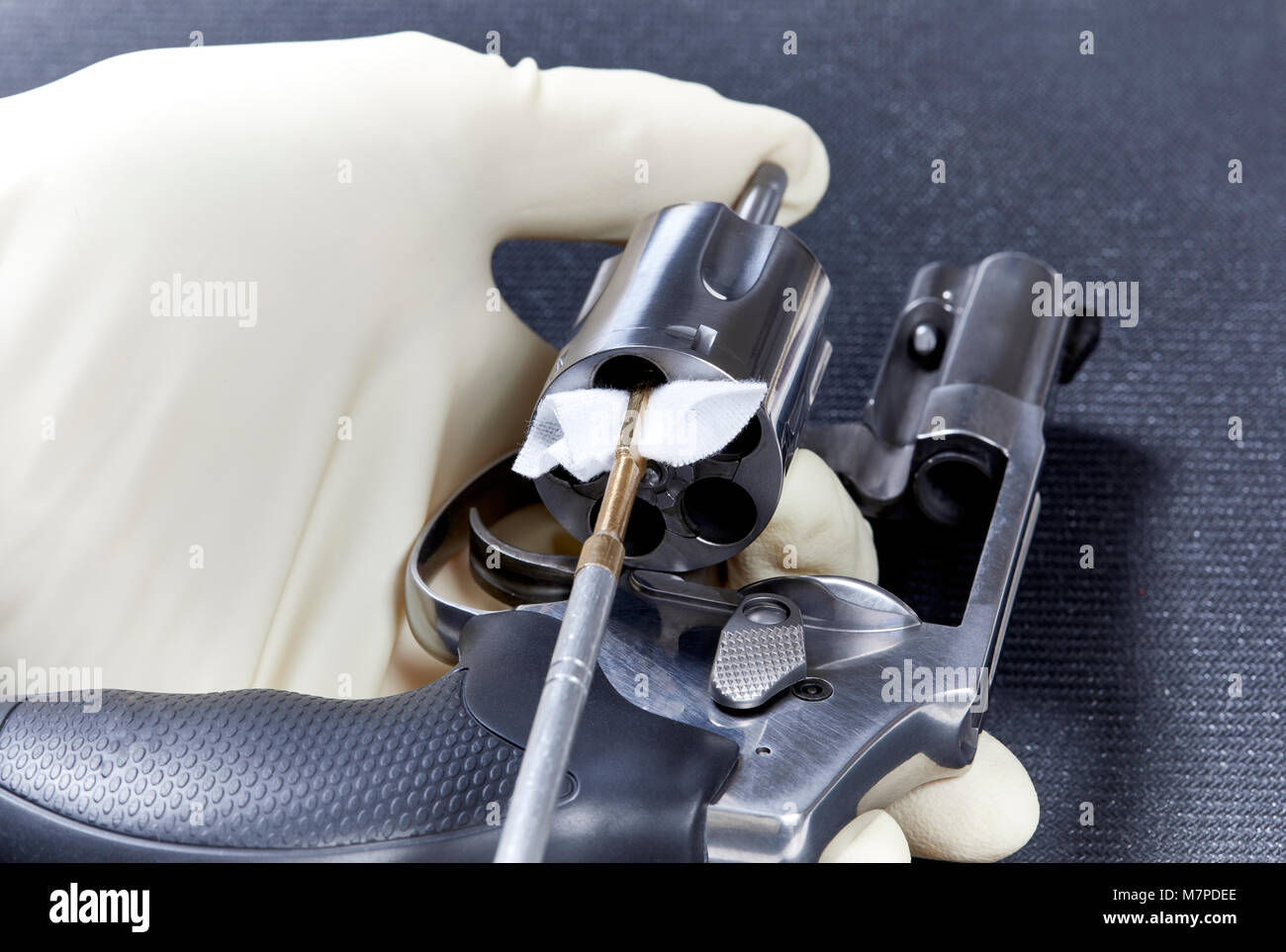 Hand inserting cleaning rod with a cotton patch into chamber of a ...