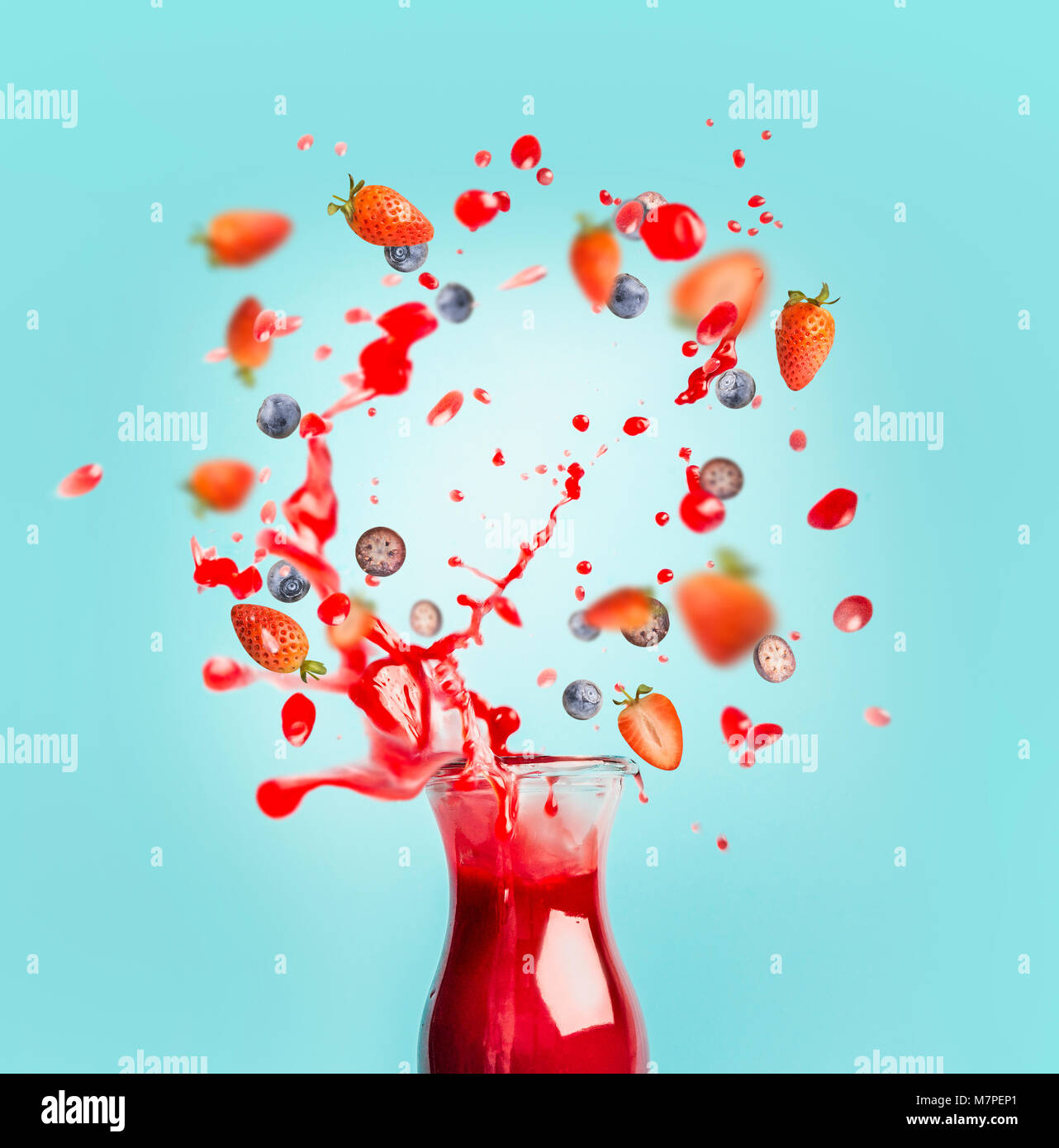 Red juice or smoothie drink is poured out of glass bottle with splash ...