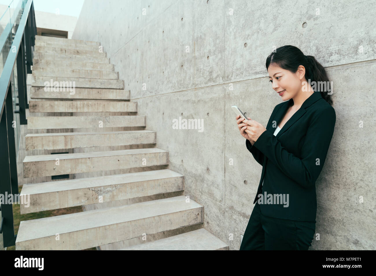 professional young Asian woman standing on the stair texting message to ...