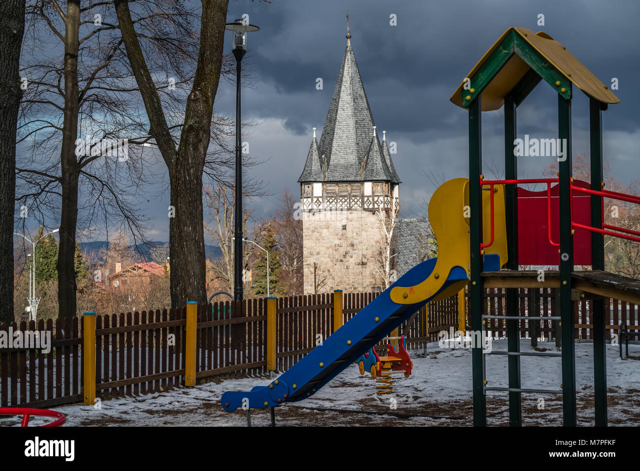 Children playground slide in the foreground of the tower of the Church ...