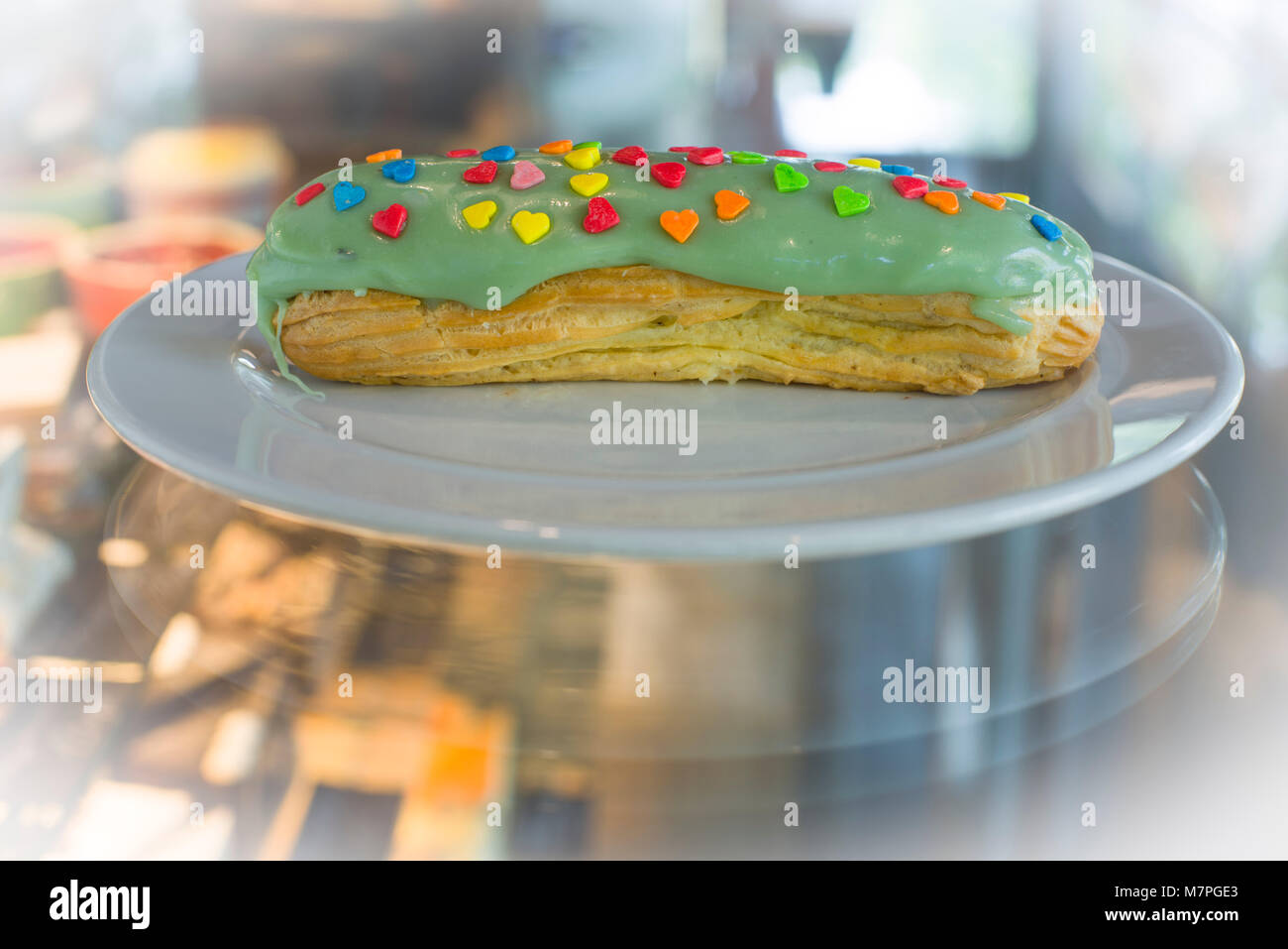 Eclair, decorated with green caramel glaze and colorful sugar hearts ...