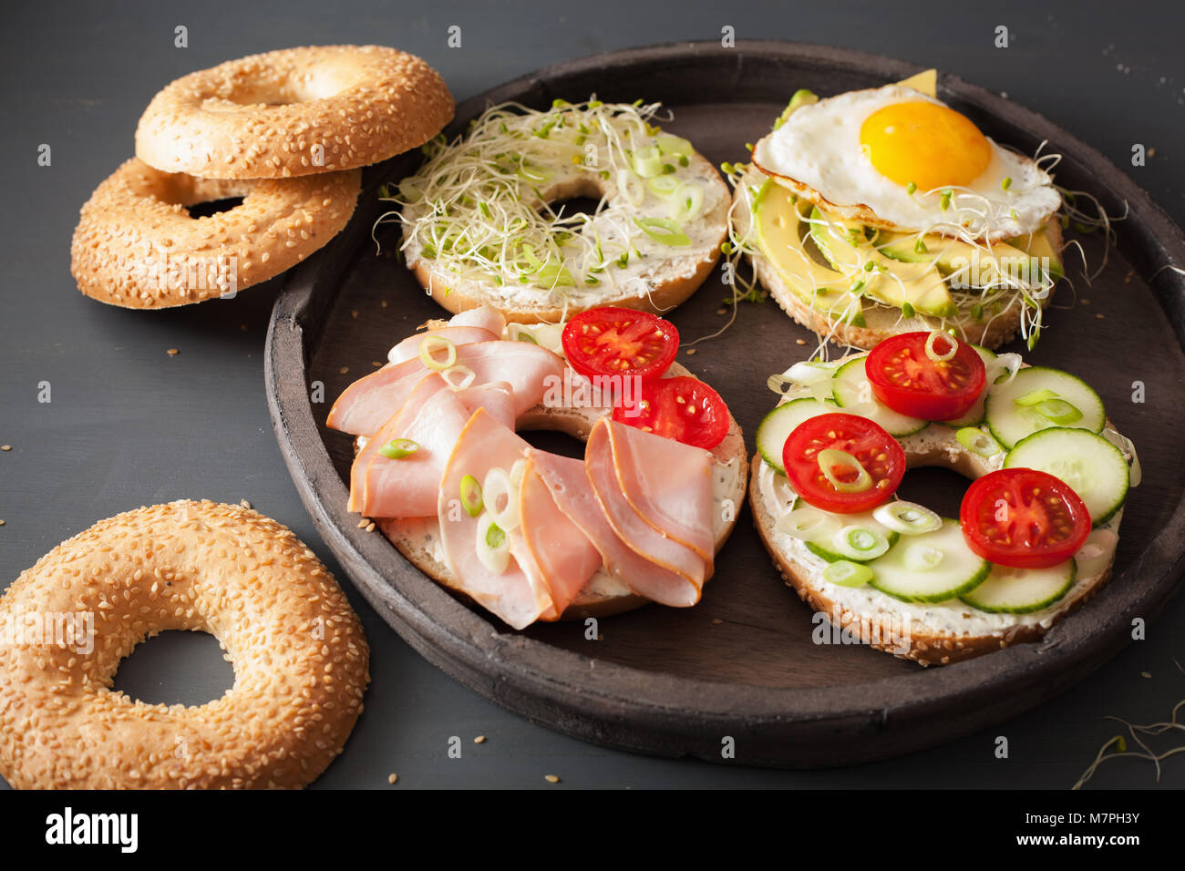 variety of sandwiches on bagels: egg, avocado, ham, tomato, soft cheese ...