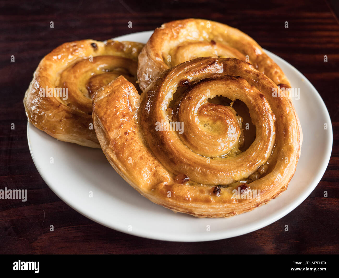 Close up of French raisin pastries on a white plate and wooden table ...