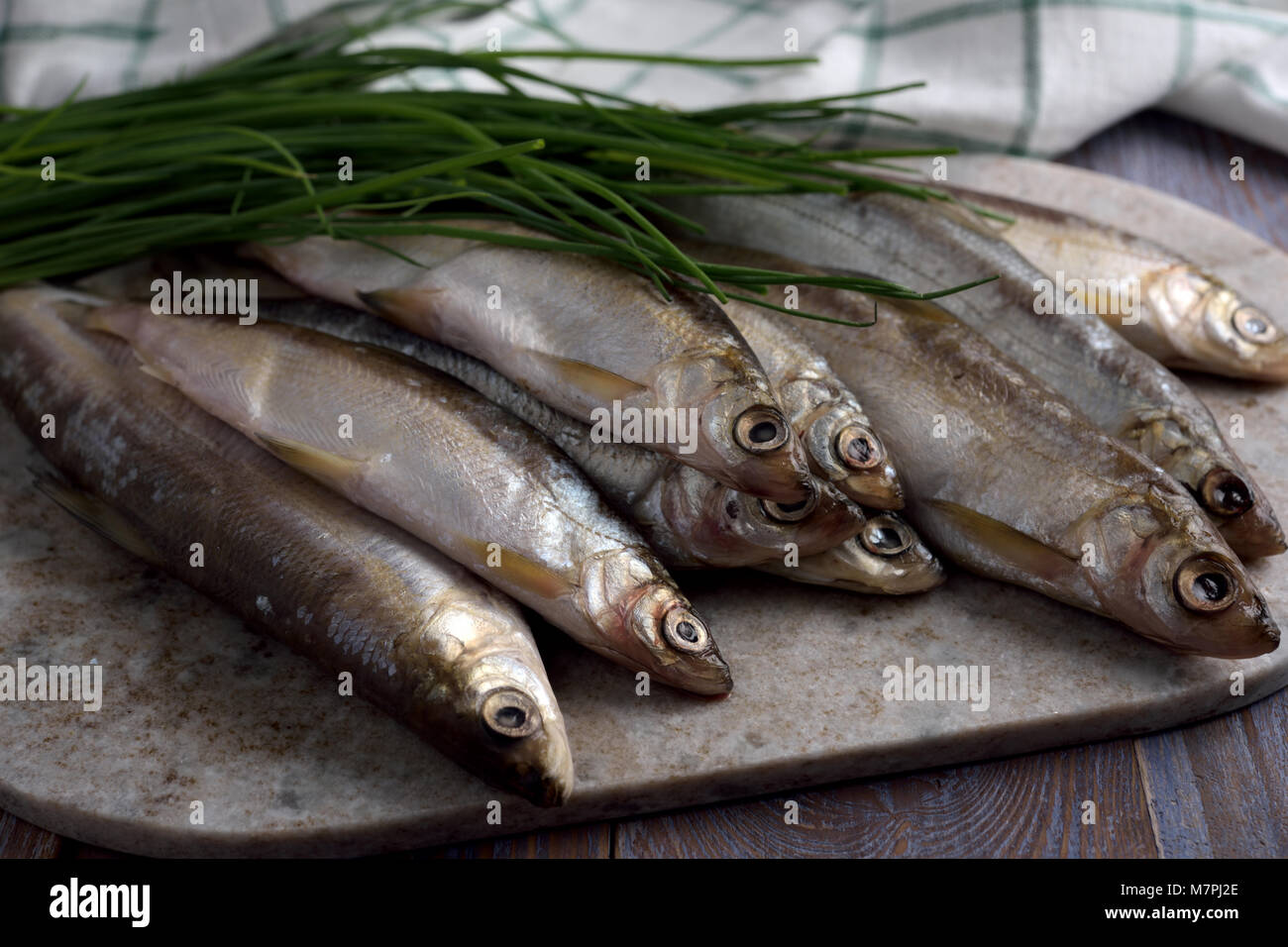 Raw vendace fish on a marble cutting board with green onion Stock Photo ...