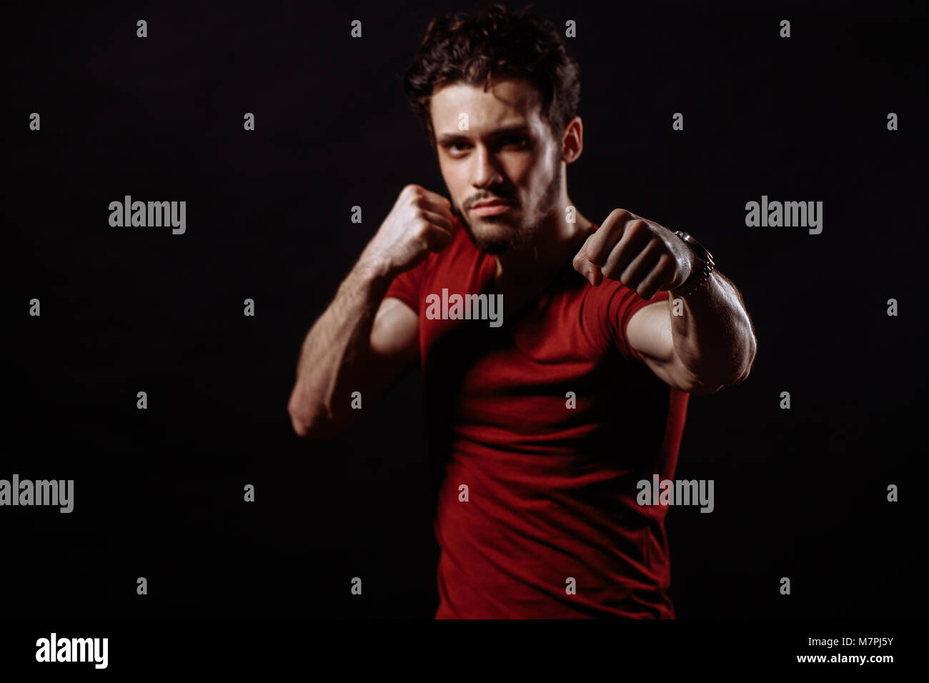 young Caucasian guy is putting up a fight with clenched fists on a ...