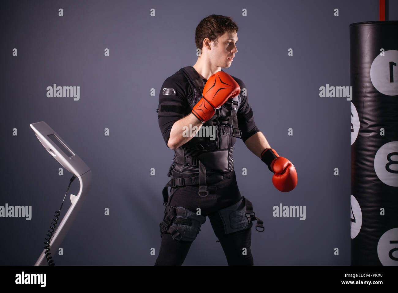 Man in boxing gloves. boxer wearing ems suit training with punching bag ...