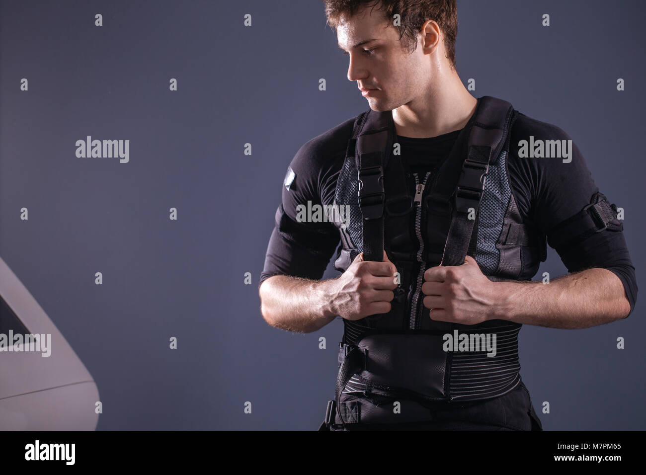 EMS, portrait of handsome man near electro muscle stimulation machine ...