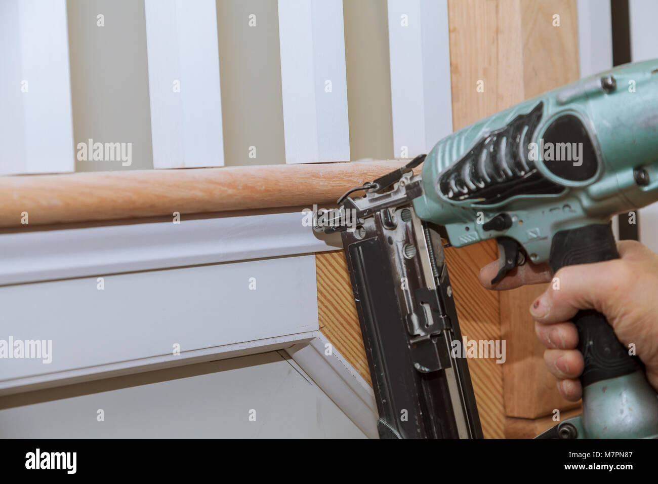 Carpenter brad using nail gun to Moulding trim, with the warning label ...