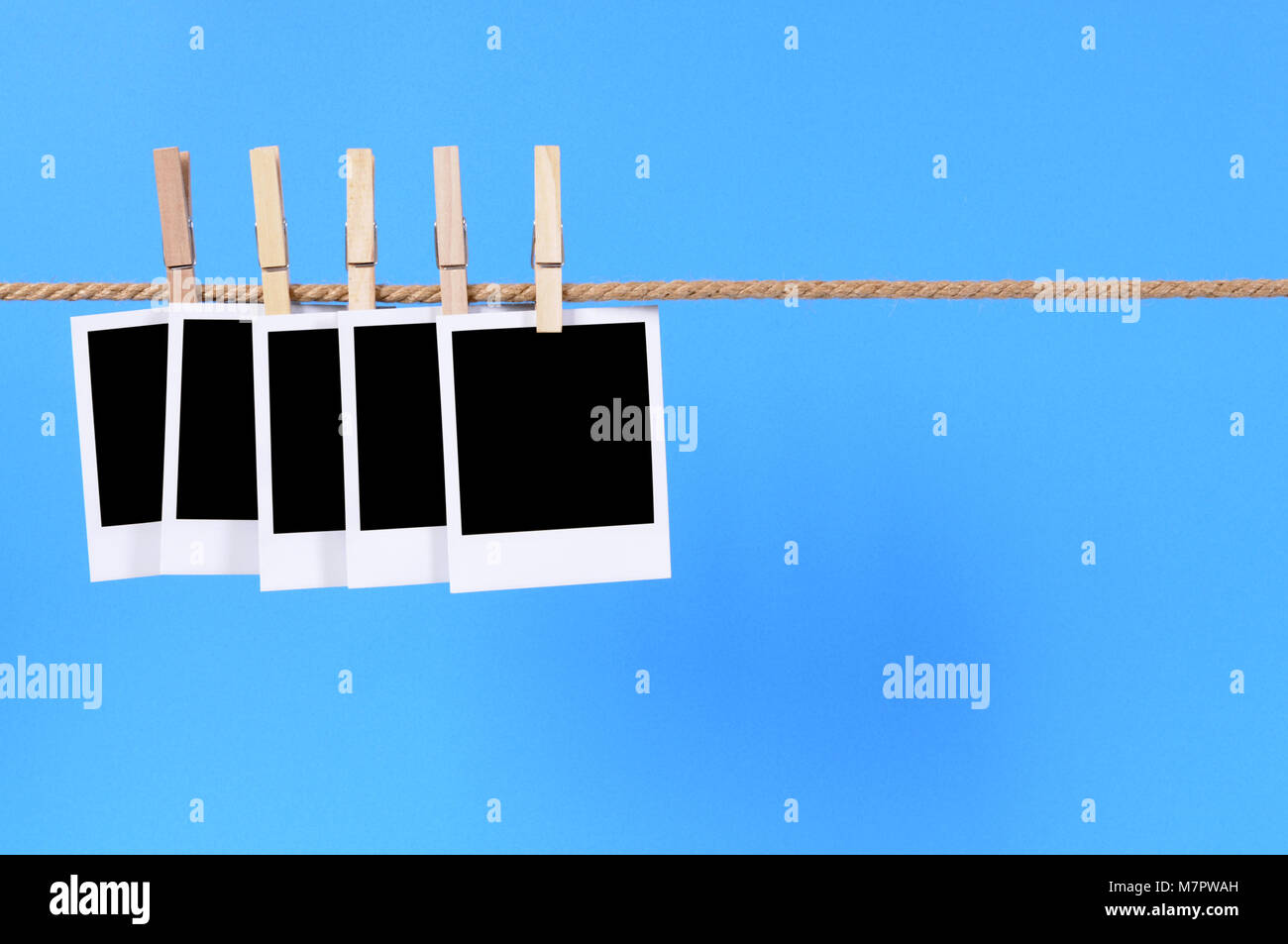 Several blank instant camera photo prints hanging on a rope or washing ...