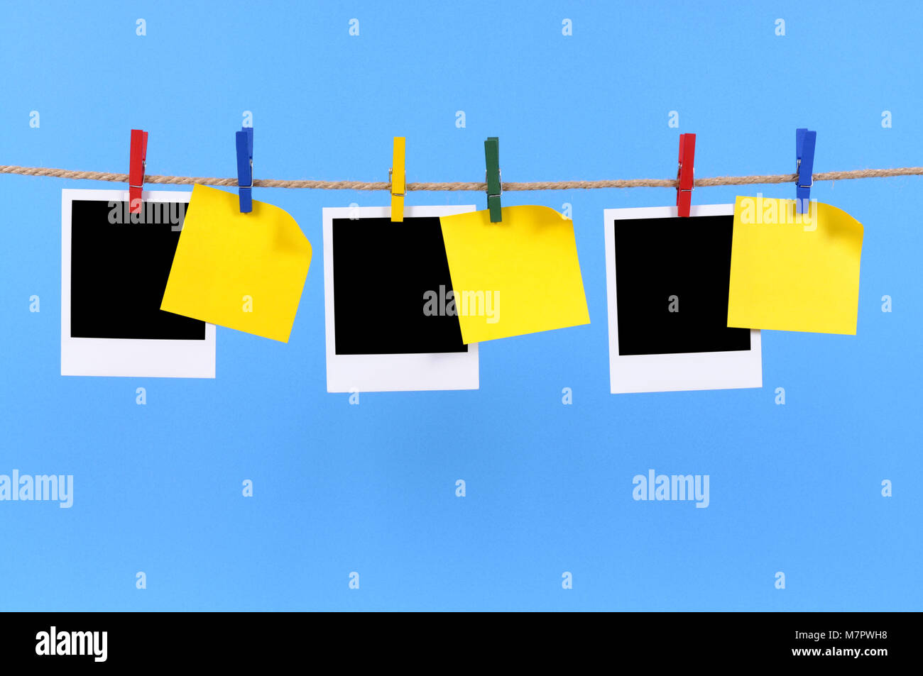 Blank instant camera photo prints and office sticky notes hanging on a ...