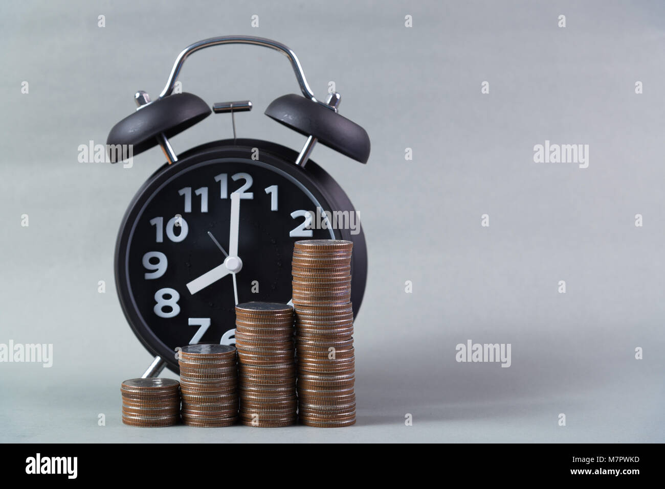 Alarm clock and step of coins stacks on working table, time for savings ...