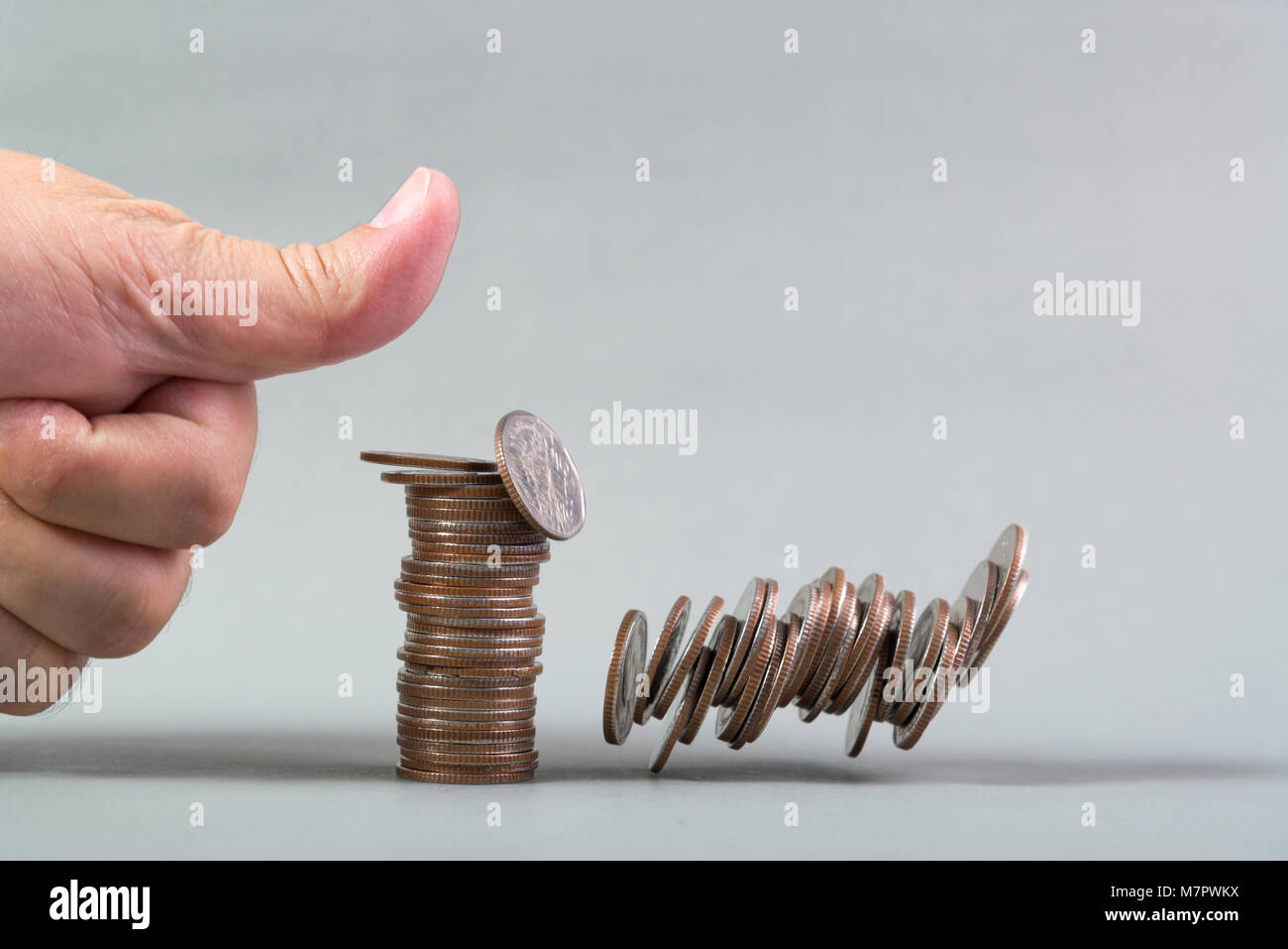 Finger pushing a pile of coins, column of coins falls , business crisis ...