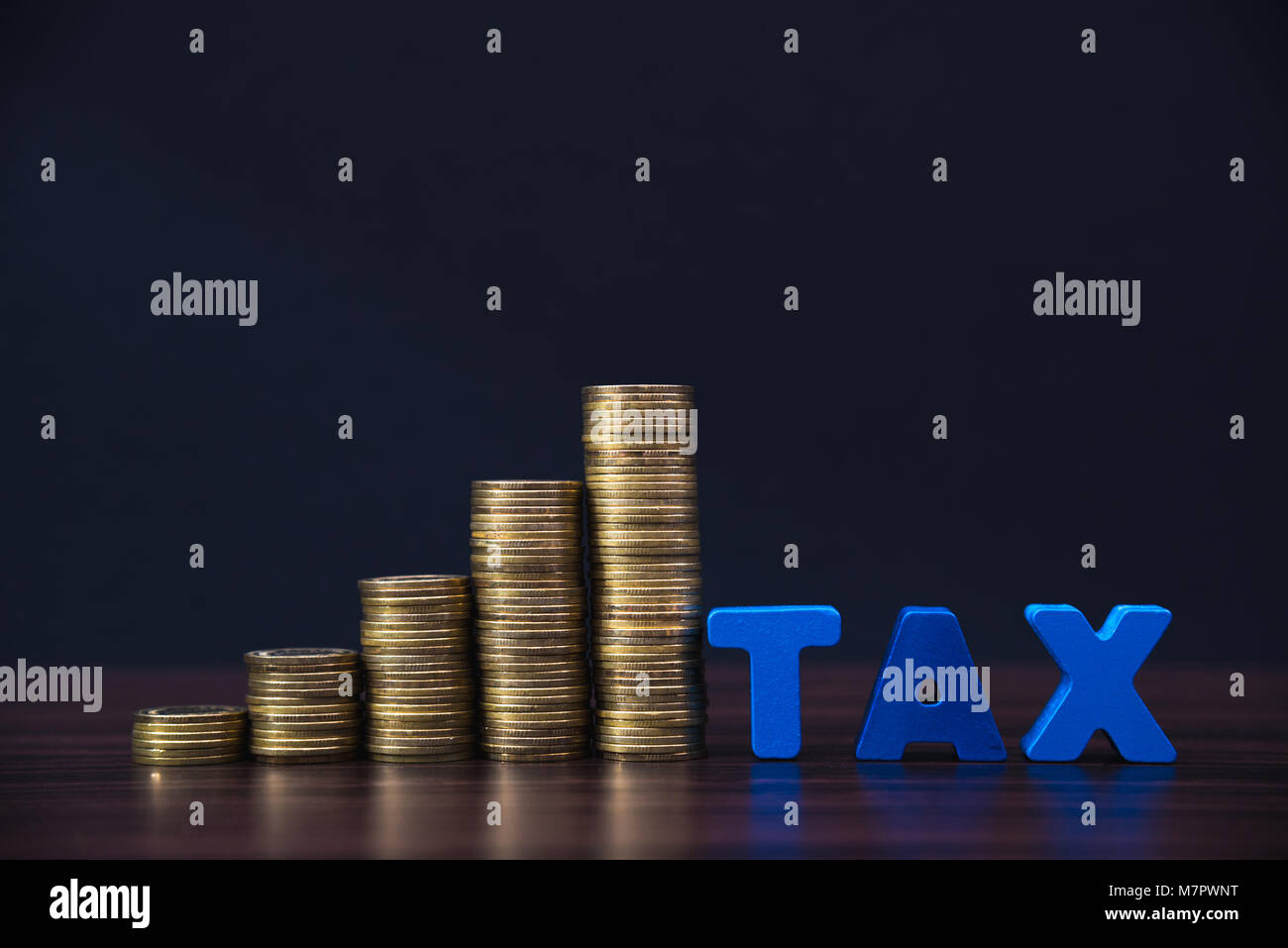 TAX concept. TAX alphabet with stack of coin in dark background ...