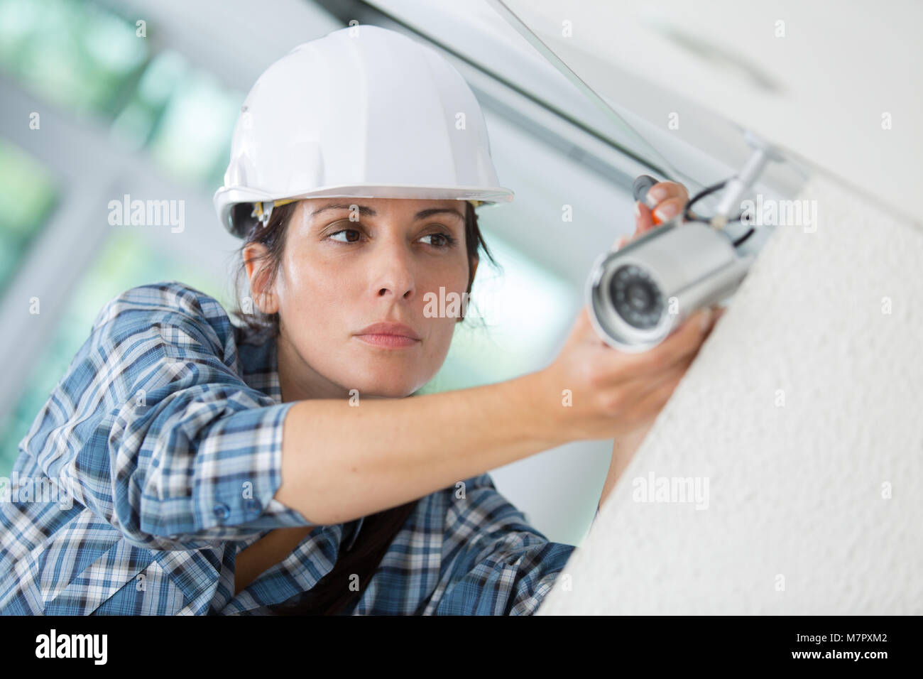 female worker placing a security cctv camera in office building Stock ...