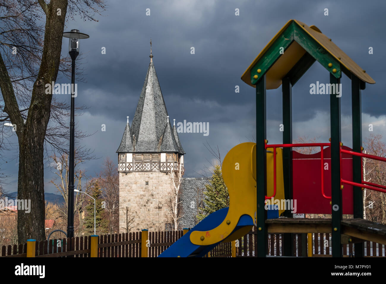 Children playground slide in the foreground of the tower of the Church ...
