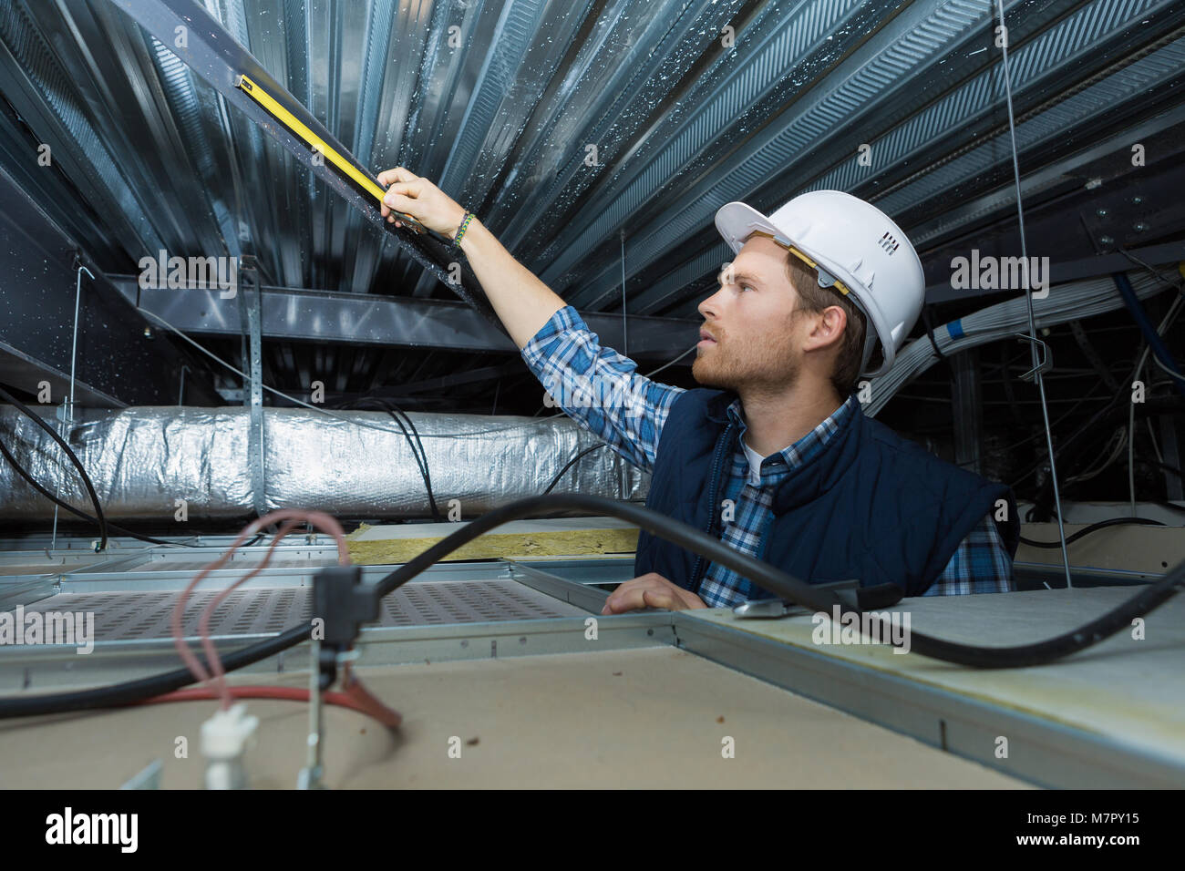 Man measuring metal bar in roof space Stock Photo - Alamy