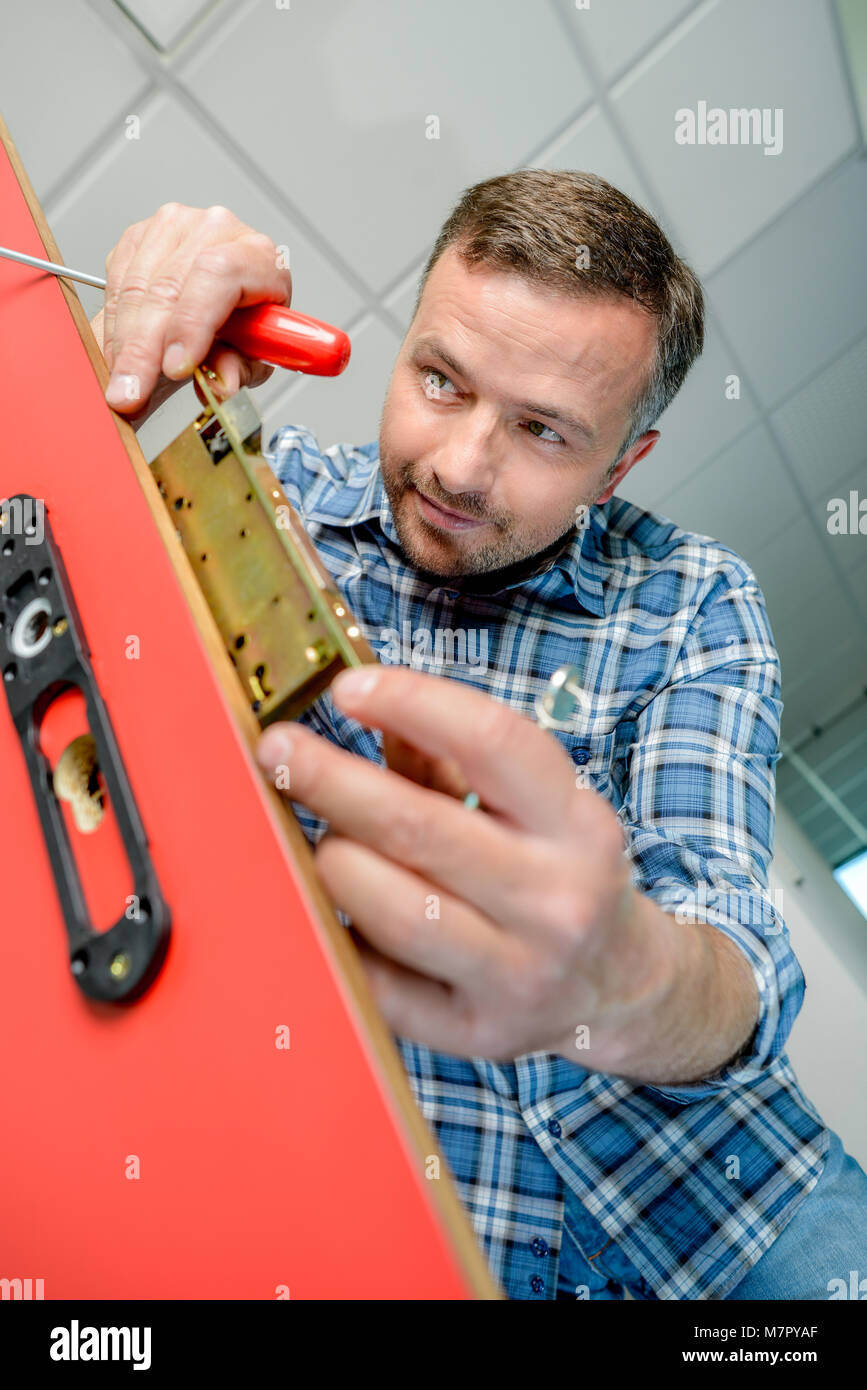 man inserting a door lock mechanism Stock Photo - Alamy