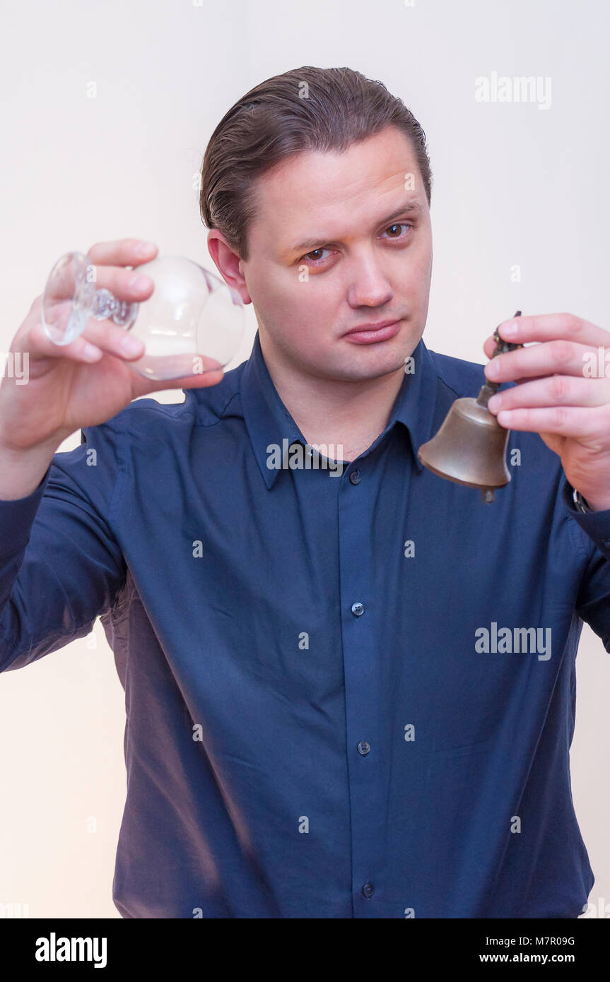 Portrait of young Caucasian Ethnicity man ringing a small bell in one ...