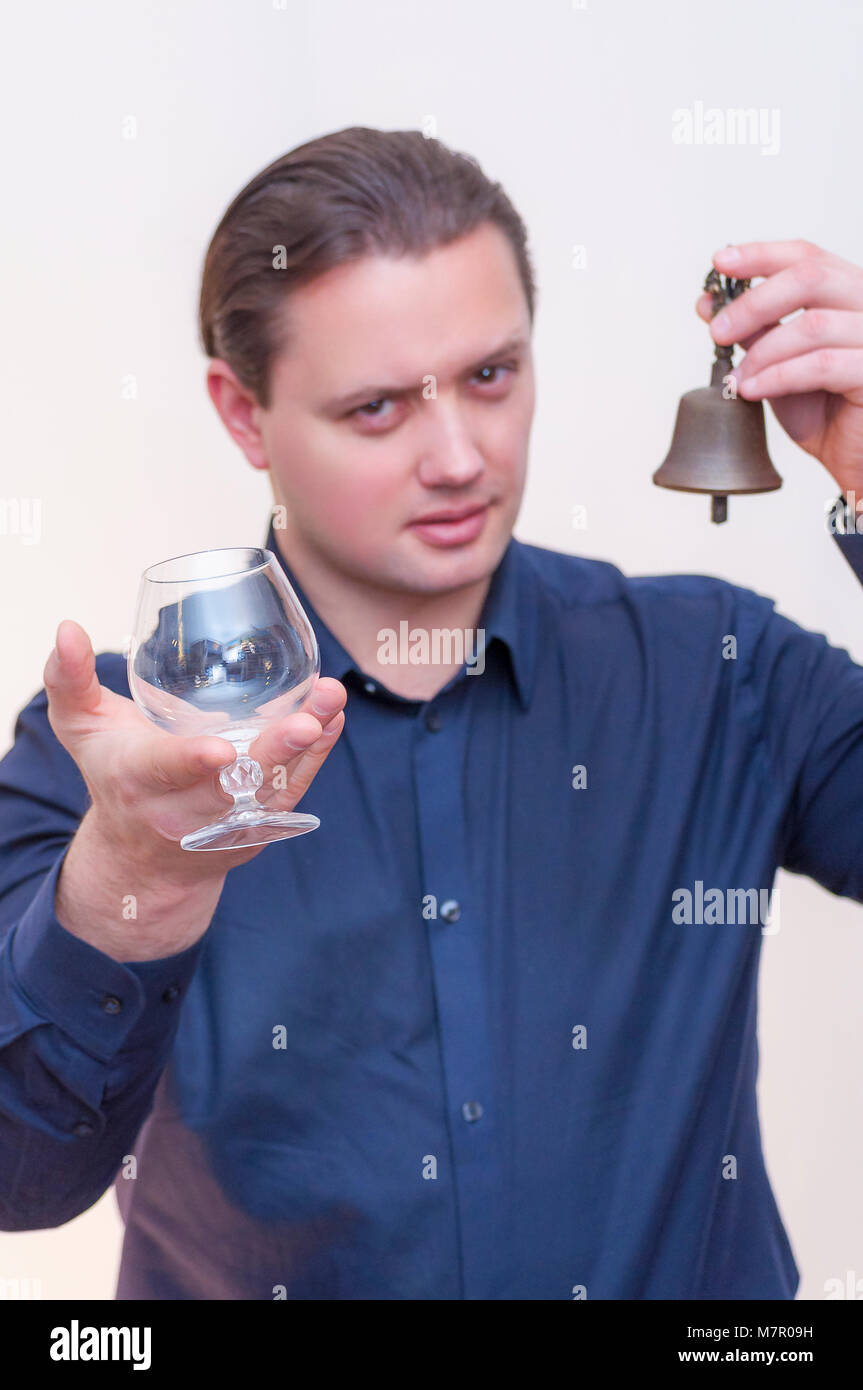 Portrait of young Caucasian Ethnicity man ringing a small bell in one ...