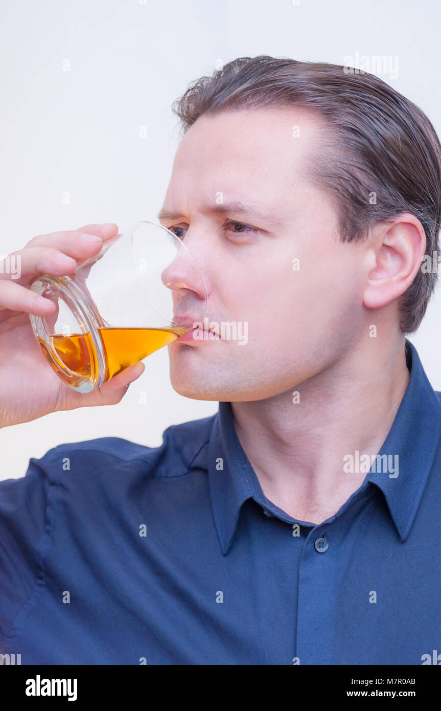 Portrait of young Caucasian Ethnicity man with blue shirt drinking ...