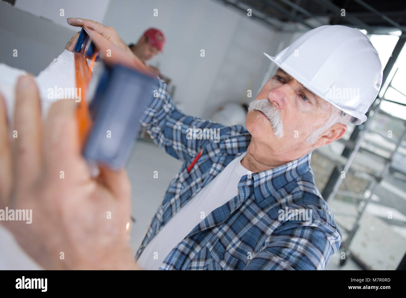Senior worker using tape measure Stock Photo - Alamy