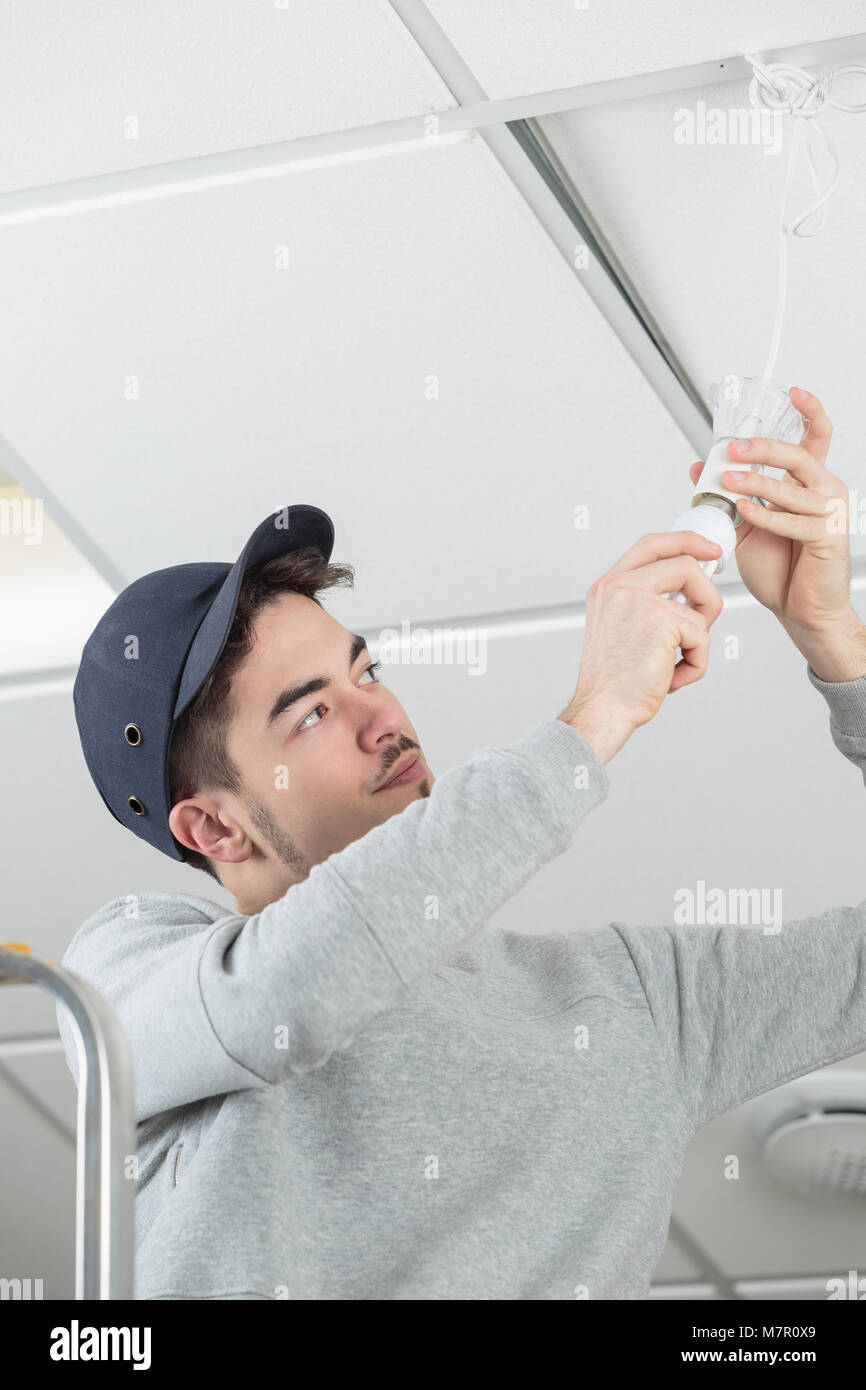 Young man changing lightbulb Stock Photo - Alamy