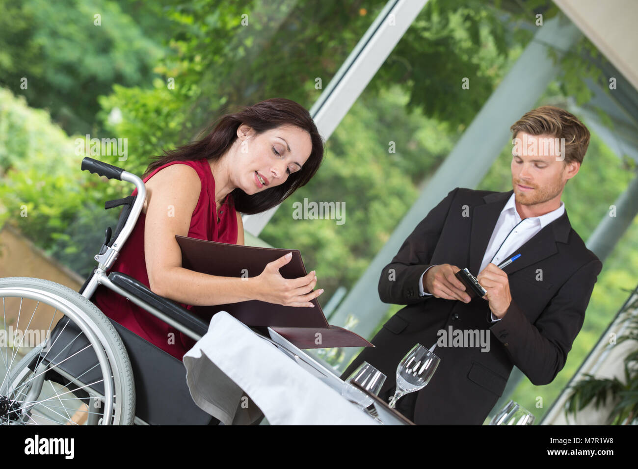 beautiful disabled woman ordering menu to waiter at the restaurant ...