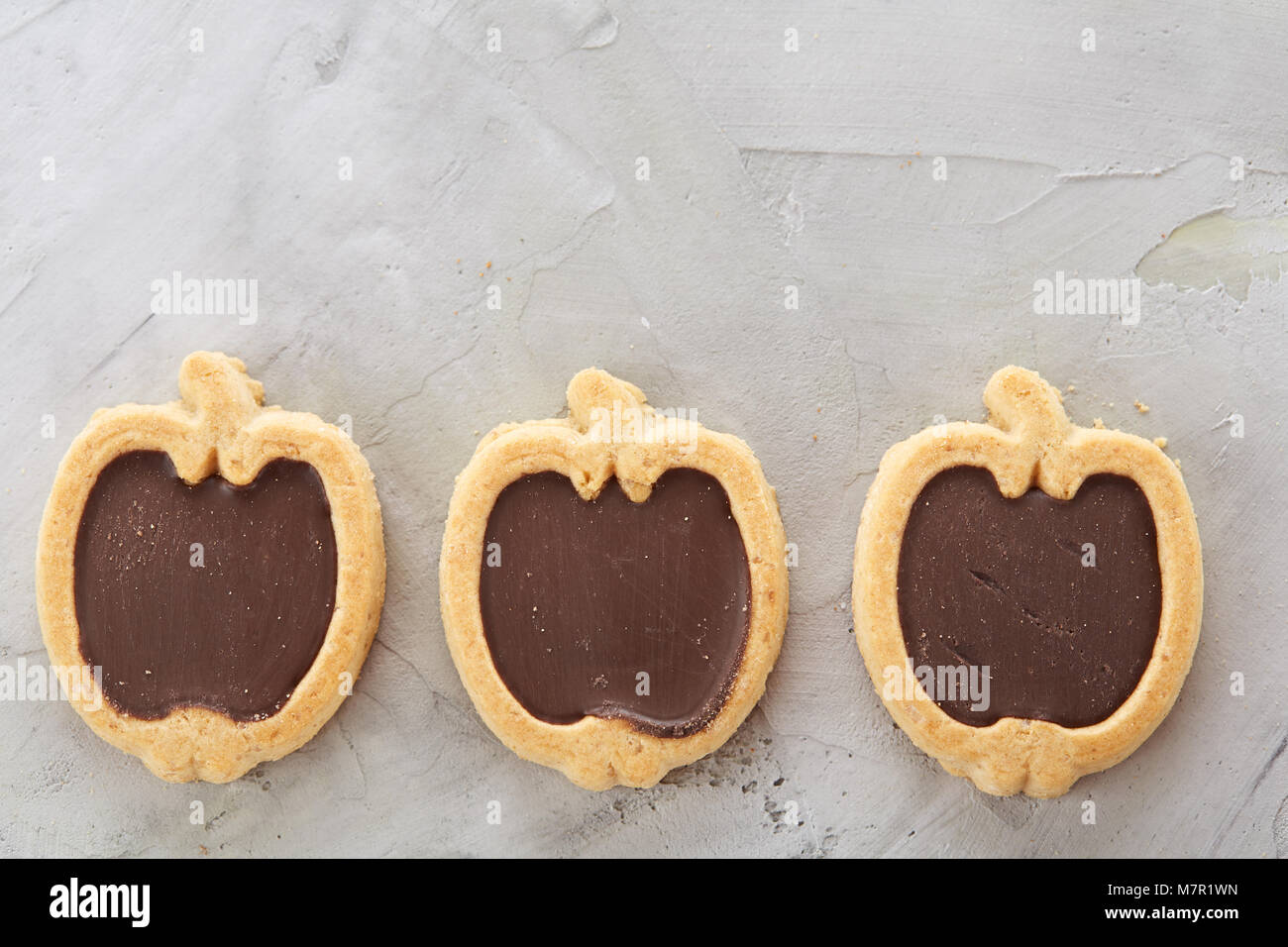 Sweet apple shaped cookies arranged in rows on light textured ...