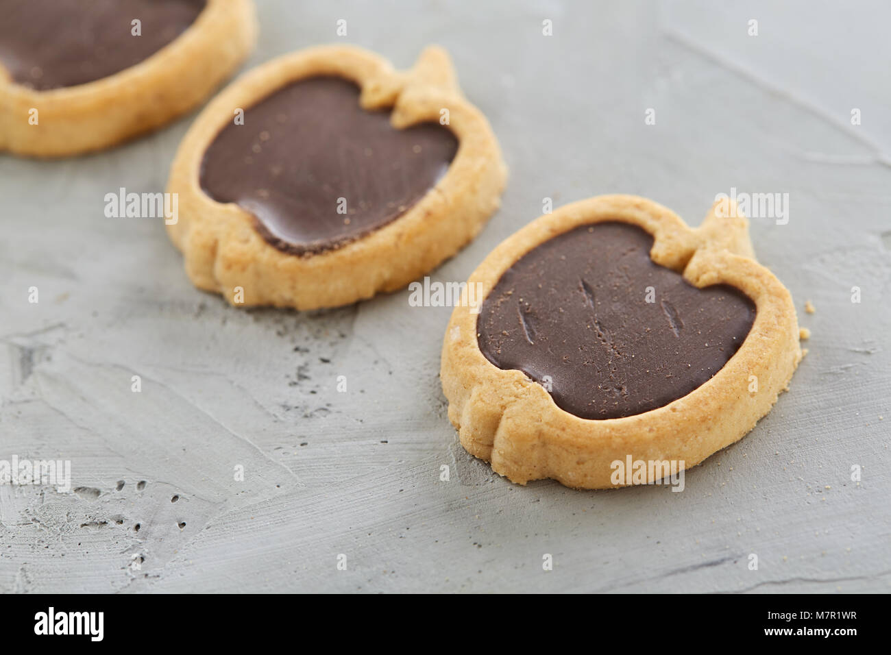 Sweet apple shaped cookies arranged in rows on light textured ...