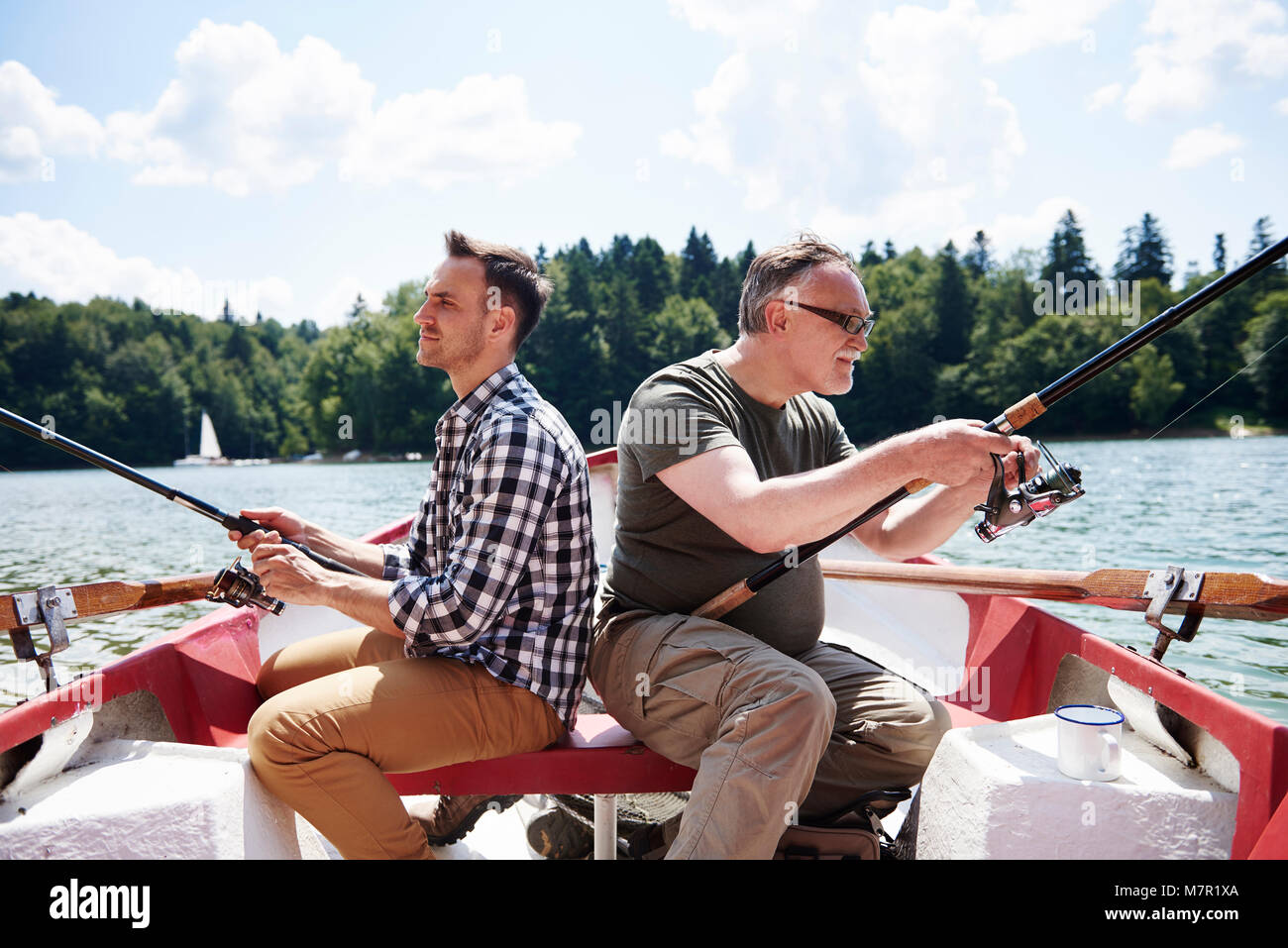 Focused men fishing on a rowboat Stock Photo - Alamy