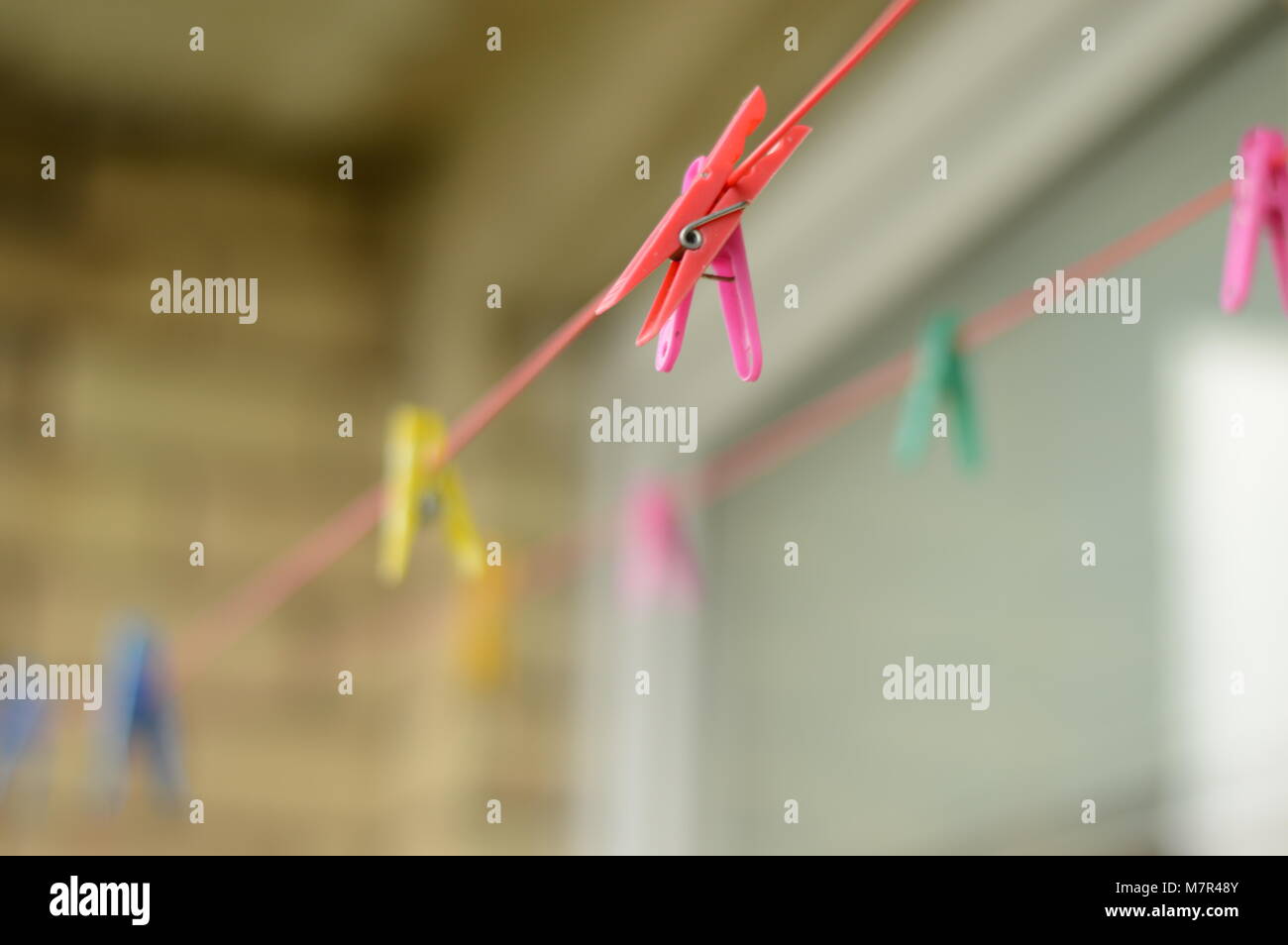 Colour clothes-pegs hanging on rope in balcony Stock Photo - Alamy