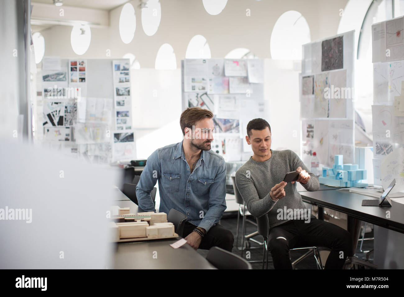 Designers looking at smartphone in creative workspace Stock Photo - Alamy