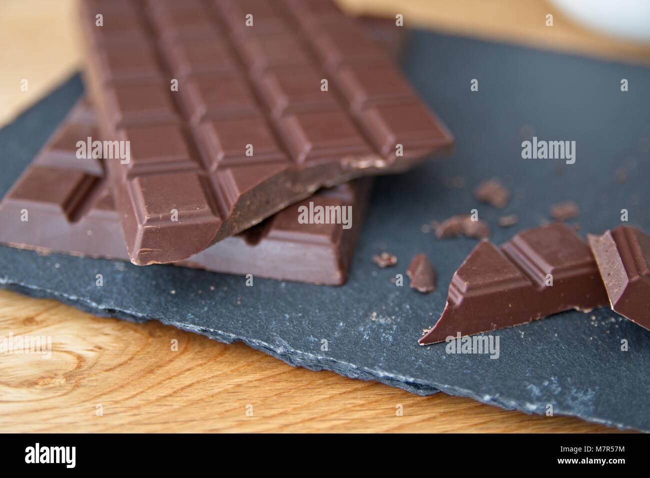 Broken plain chocolate bar on slate background Stock Photo - Alamy