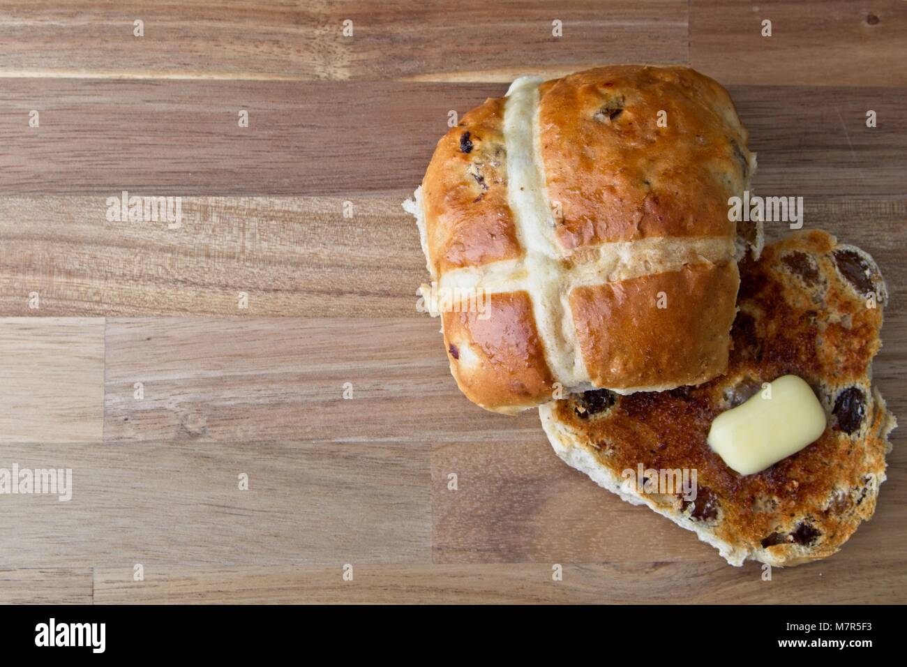 Toasted hot cross bun with melting butter on wooden surface Stock Photo ...