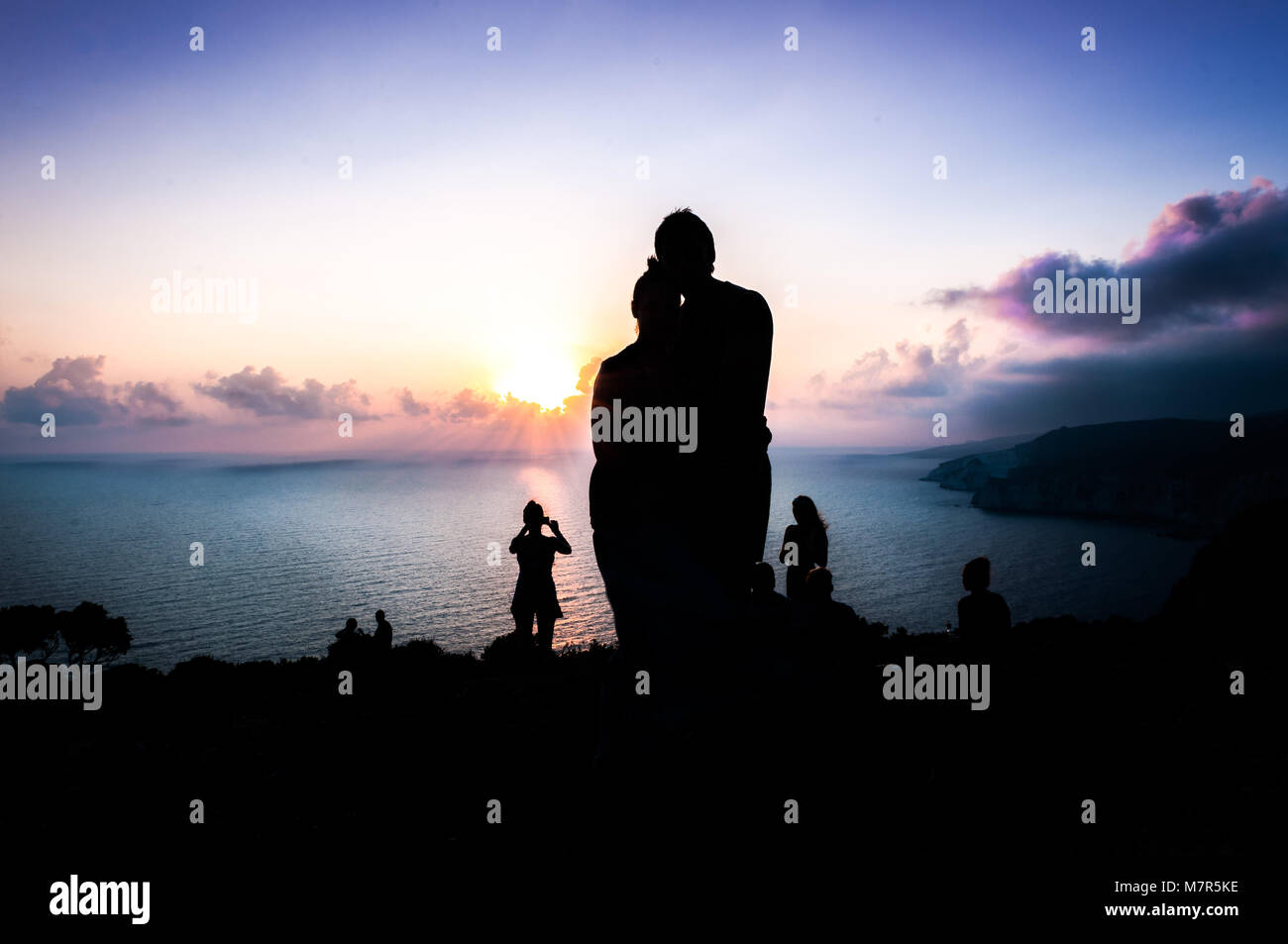 People watching sunset on the beach. Back view of a couple silhouette ...