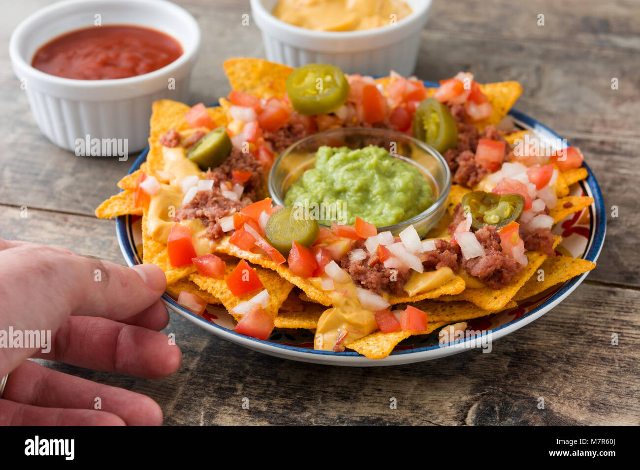 People eating mexican nachos with beef, guacamole, cheese sauce ...