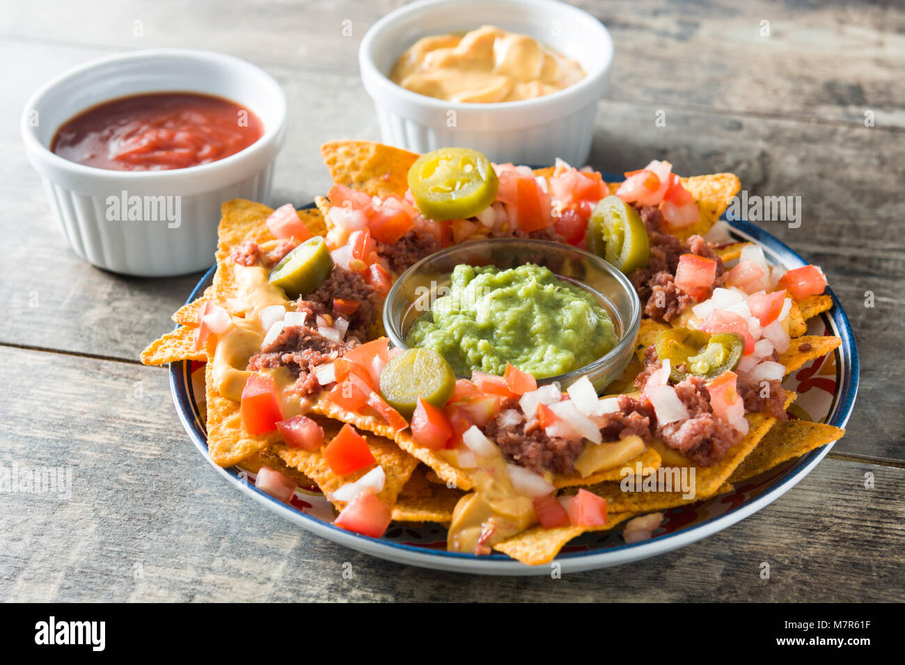 Mexican nachos with beef, guacamole, cheese sauce, peppers, tomato and ...
