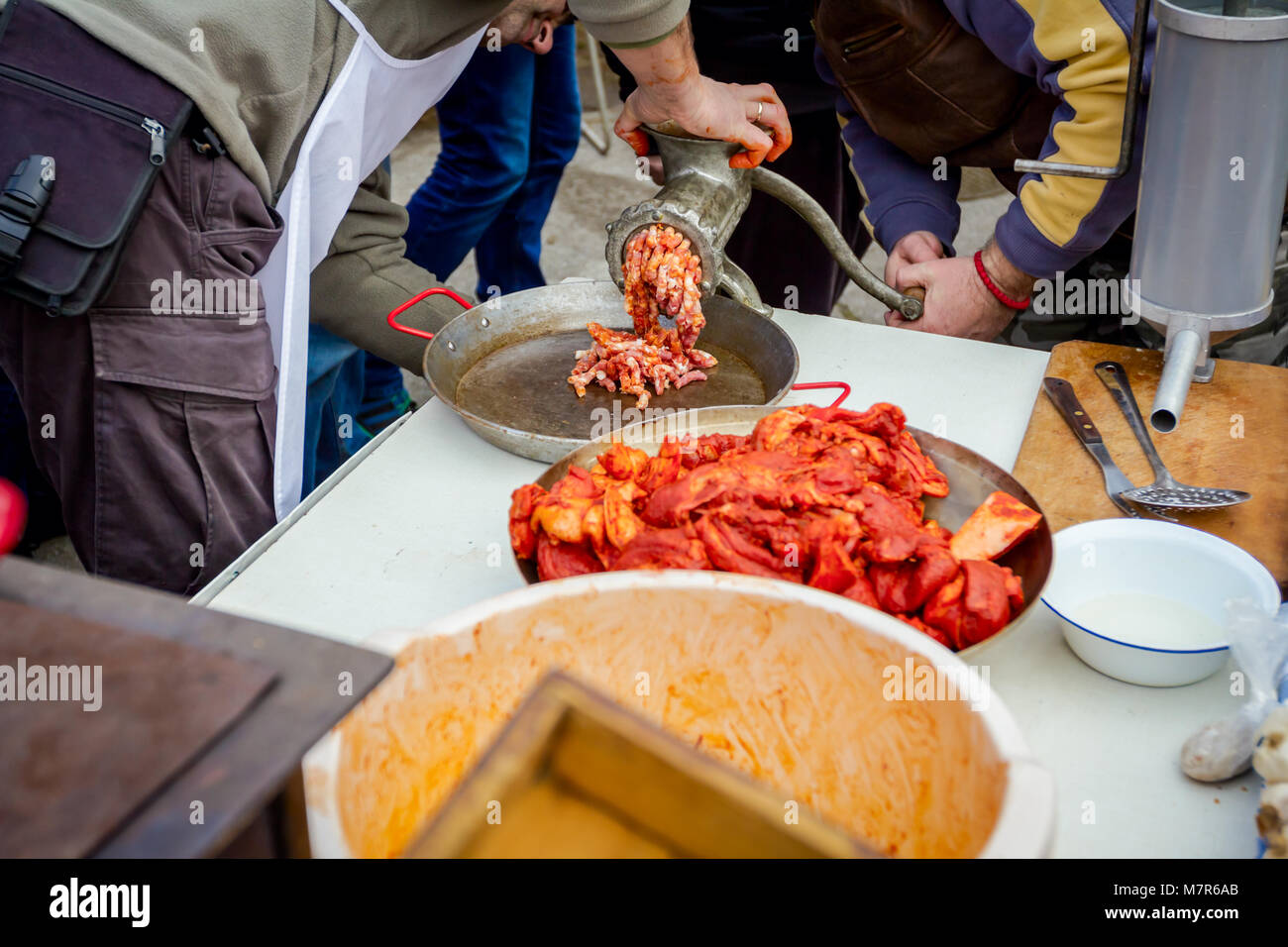 Men are working together on meat grinder machine, forcemeat process for ...
