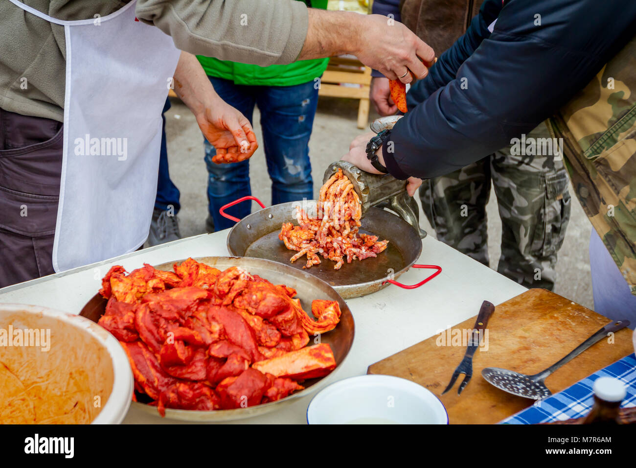 Men are working together on meat grinder machine, forcemeat process for ...