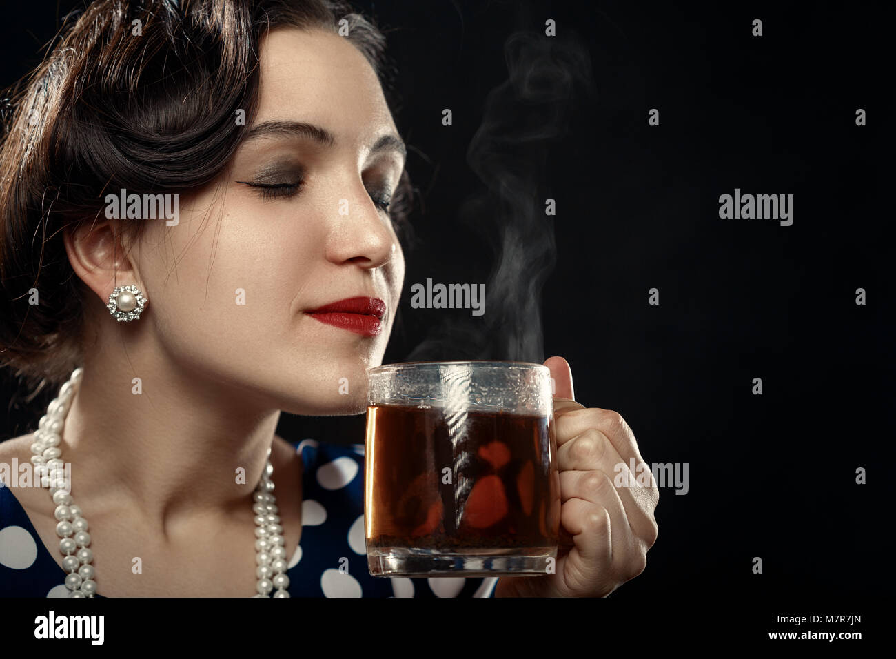beautiful pinup woman with cup of tea on black background with copy ...