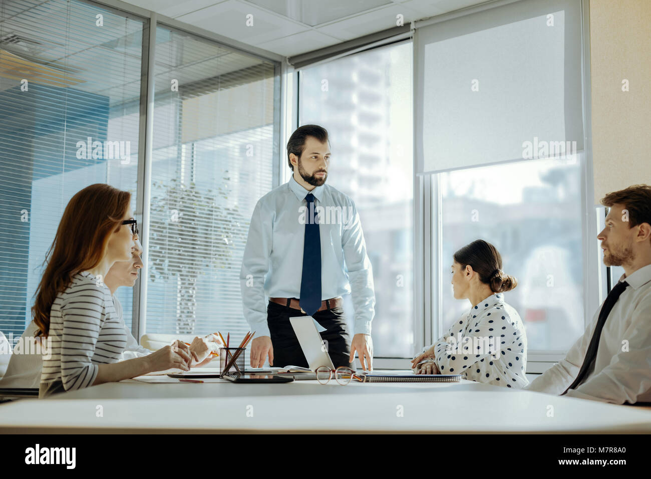Charming young man conducting meeting with employees Stock Photo - Alamy