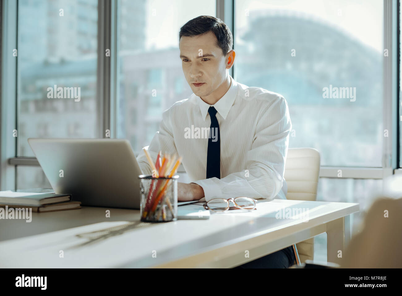 Handsome young man being focused on work on laptop Stock Photo - Alamy
